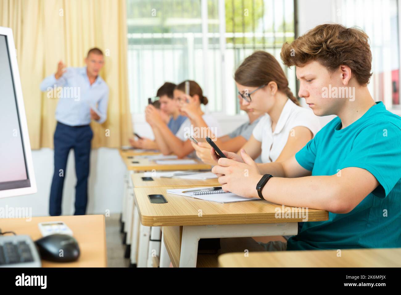 Teen pupils using mobile phones during lesson Stock Photo - Alamy