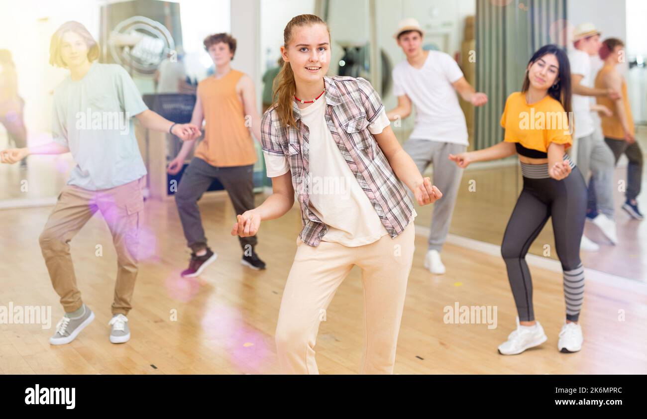 Cheerful teen girl training movements of group dance in choreography ...