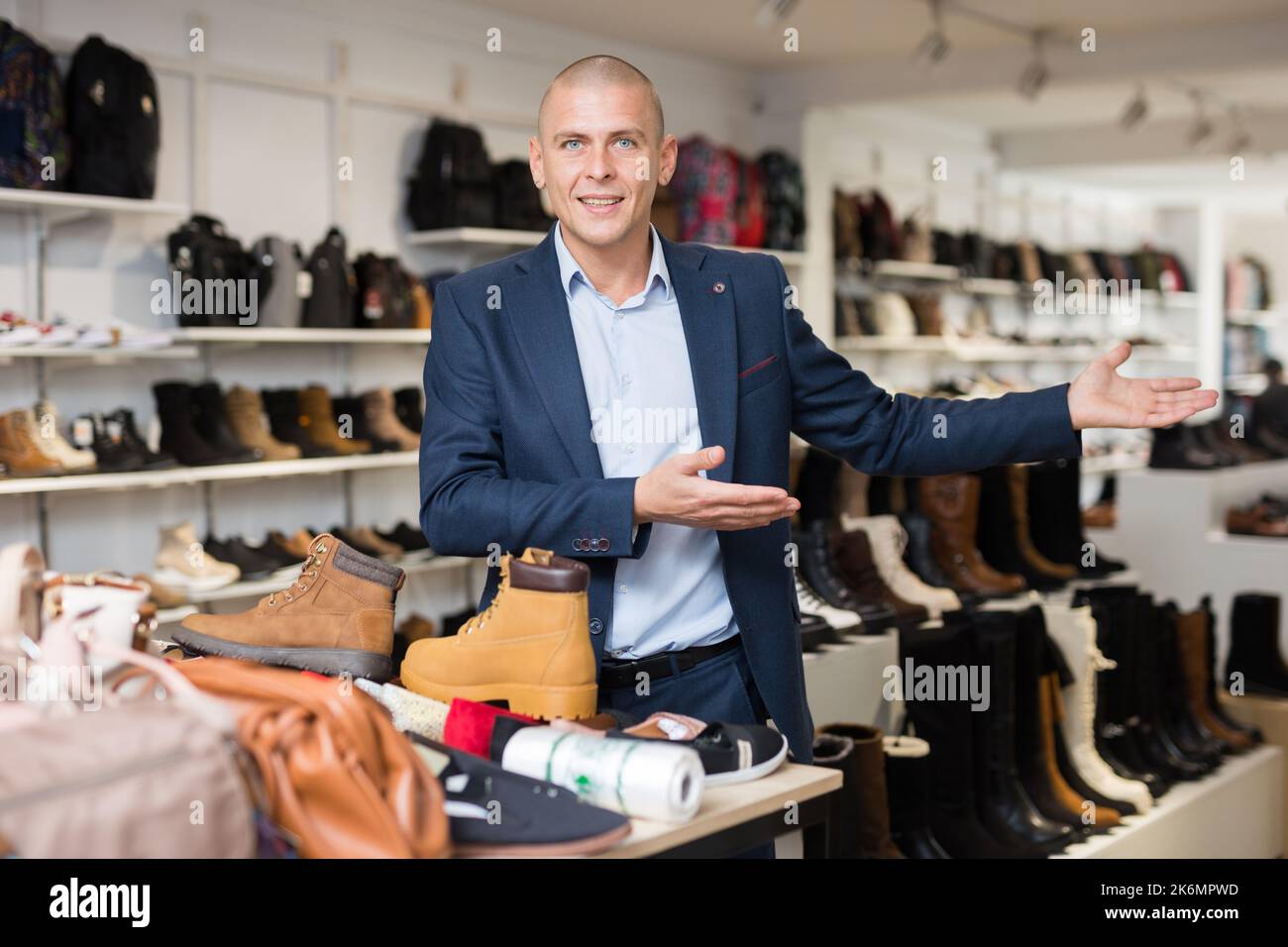 Portrait of positive friendly salesman inviting to shoe store Stock ...