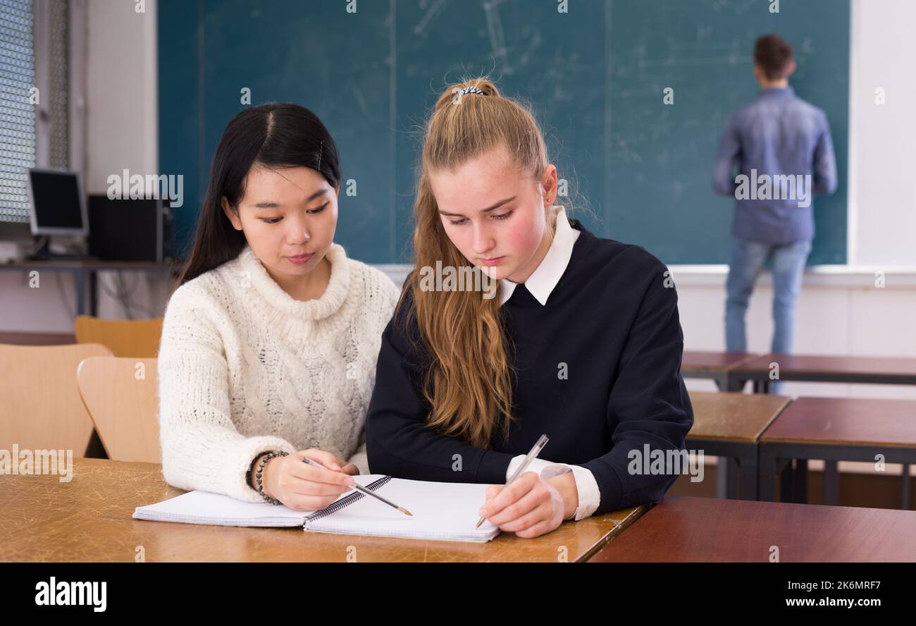 Tired female students during writing notes in classroom Stock Photo - Alamy