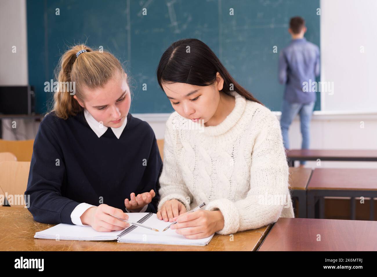 Tired female students during writing notes in classroom Stock Photo - Alamy