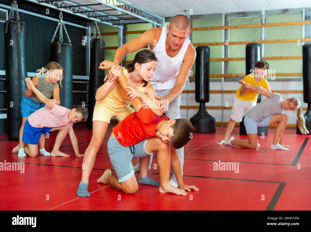 Coach teaches children to apply self-defense techniques in gym Stock ...