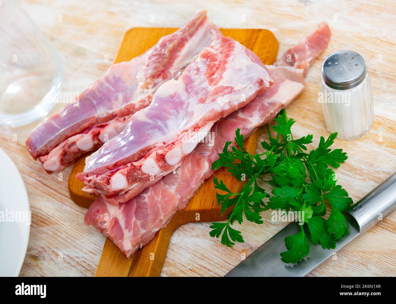 Raw meaty pork ribs slabs with greens on wooden cutting board Stock ...