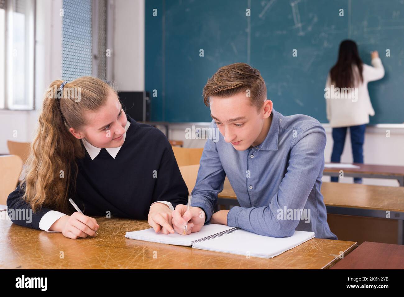 Girl student explaining study material to classmate Stock Photo - Alamy