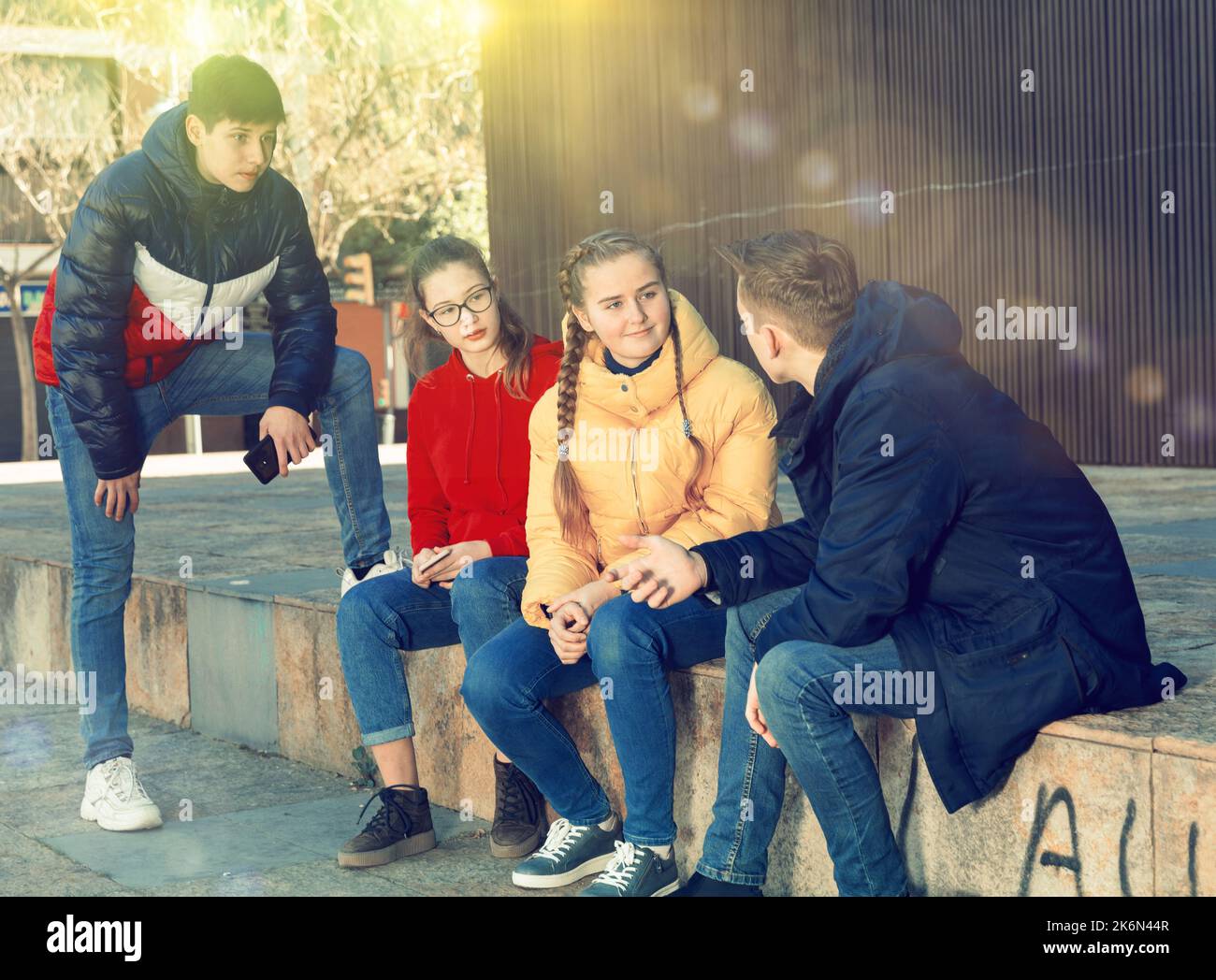Four teenagers enthusiastically look at the screens of their ...