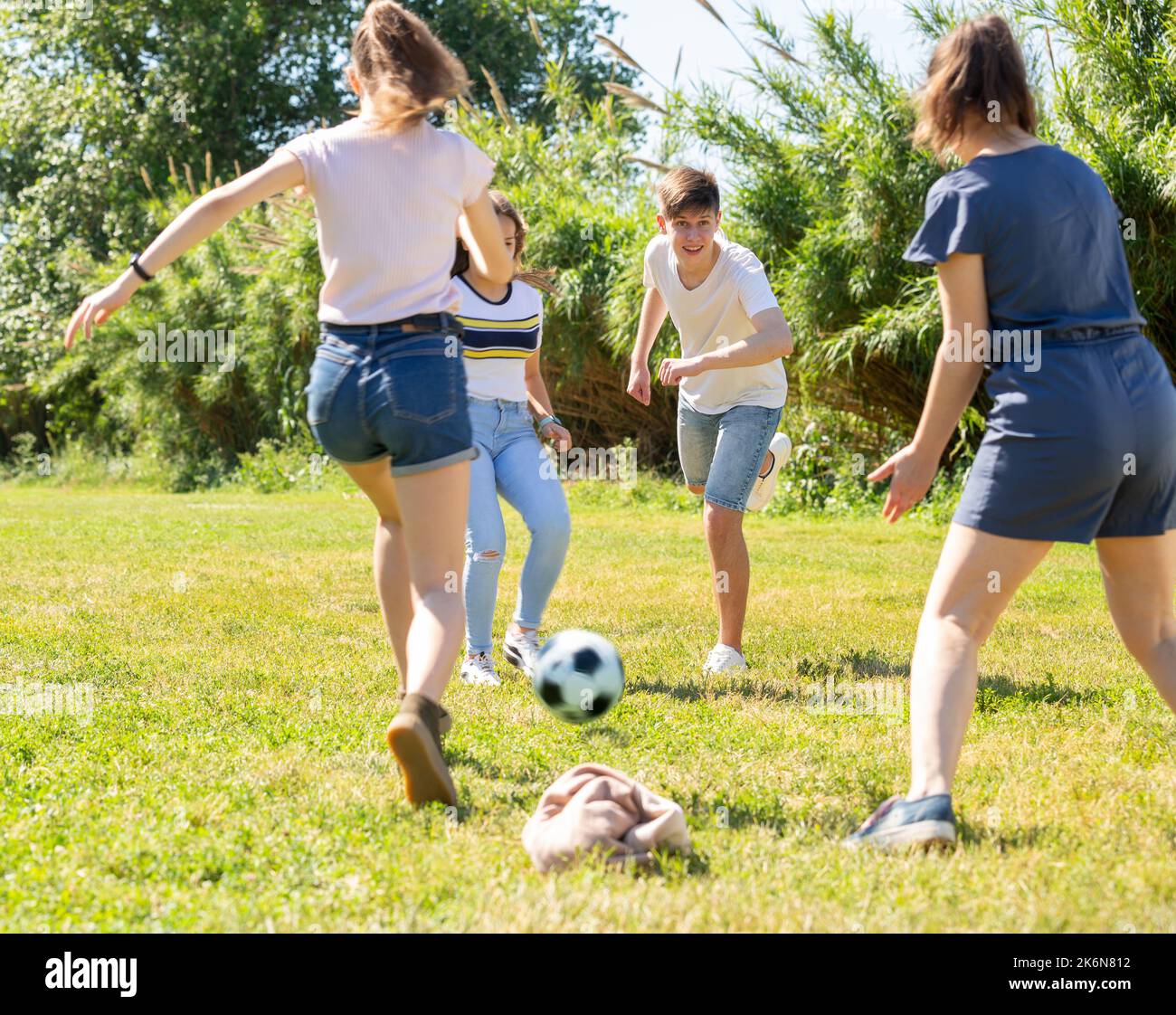 Company of glad teenagers playing football Stock Photo - Alamy