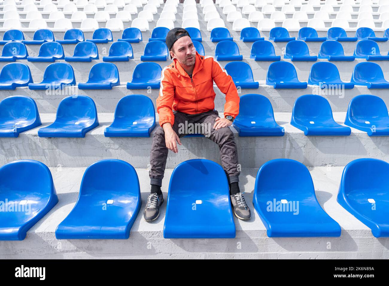 A lonely man is sitting and watching a sports competition alone on a ...