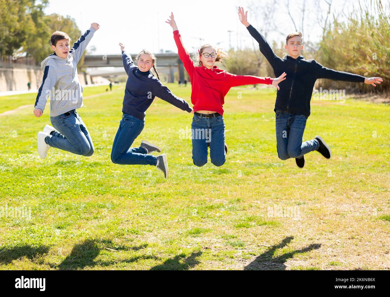 Friendly teenagers jumping together in park Stock Photo - Alamy