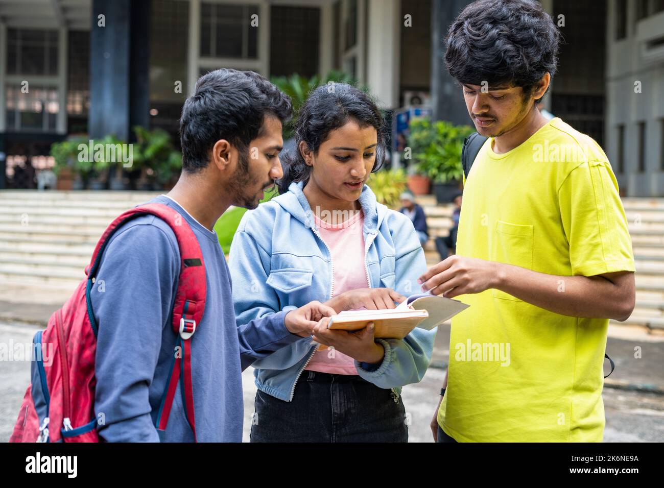 group of young indian Students busy on by discussing of syllabus during examination at college ...