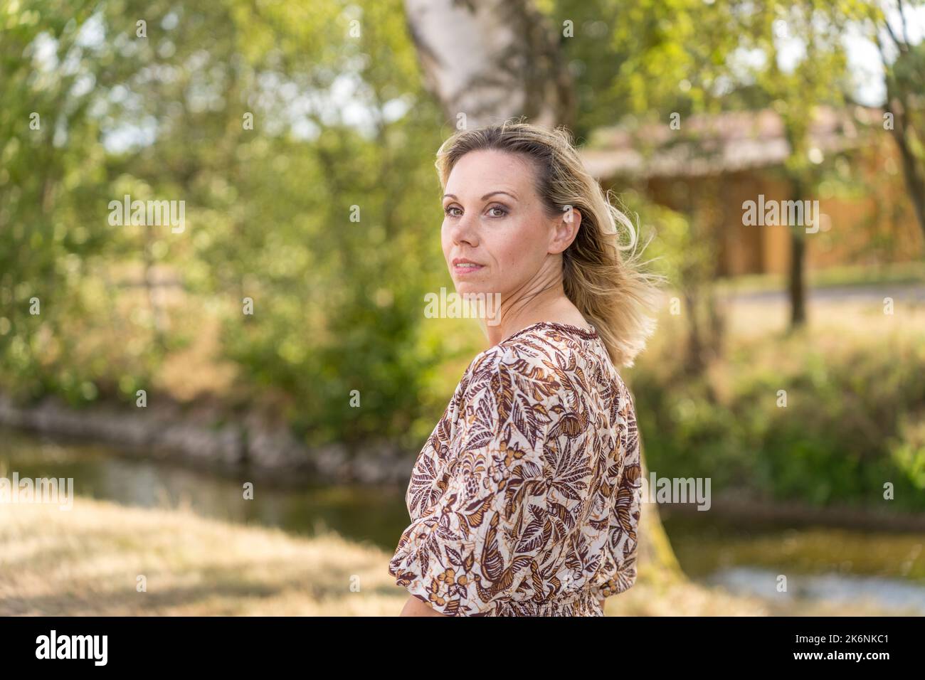 Surprised woman in her forties glancing over her left shoulder, outside ...