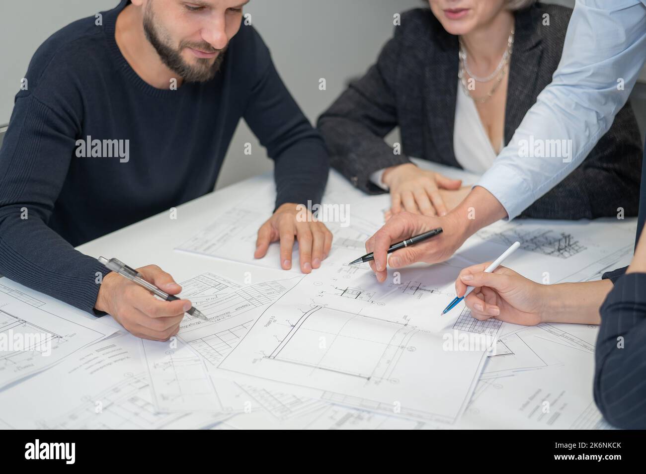 Close-up of the hands of four colleagues with blueprints on the table ...