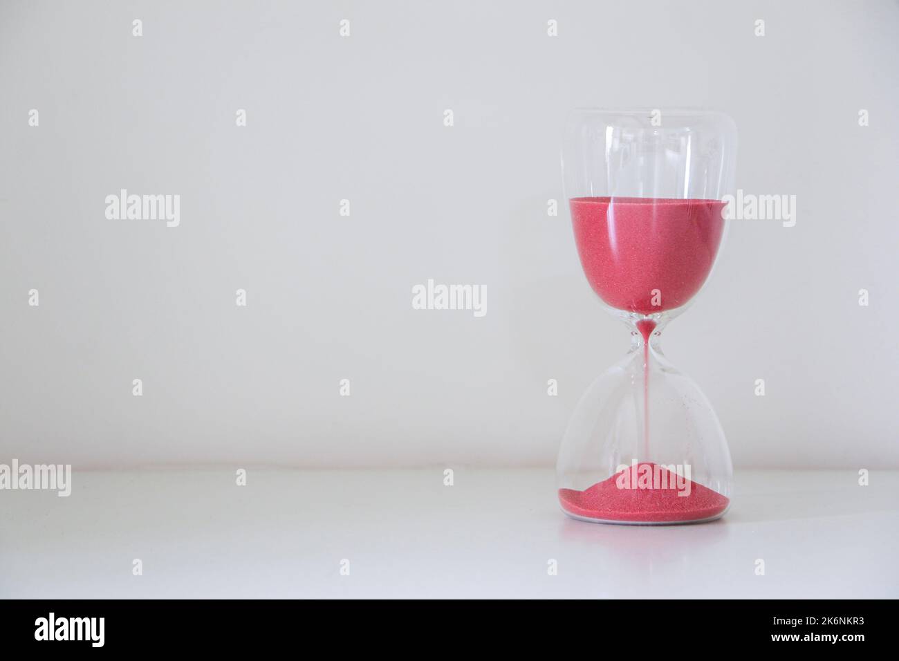 Red sand running through the bulbs of an hourglass, isolated on right ...