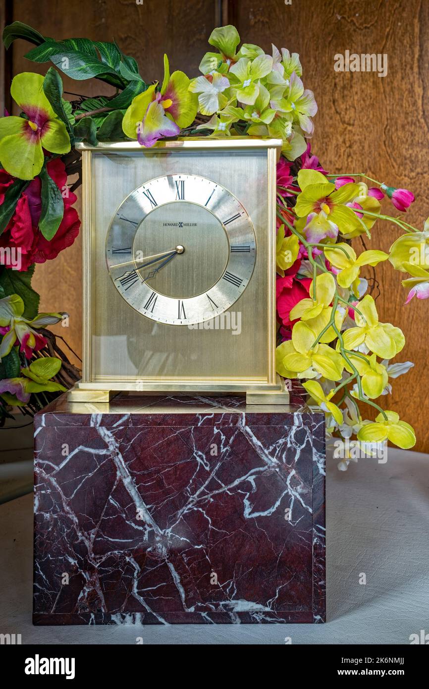 Artificial flowers adorn a Howard Miller Exton clock on display in a ...