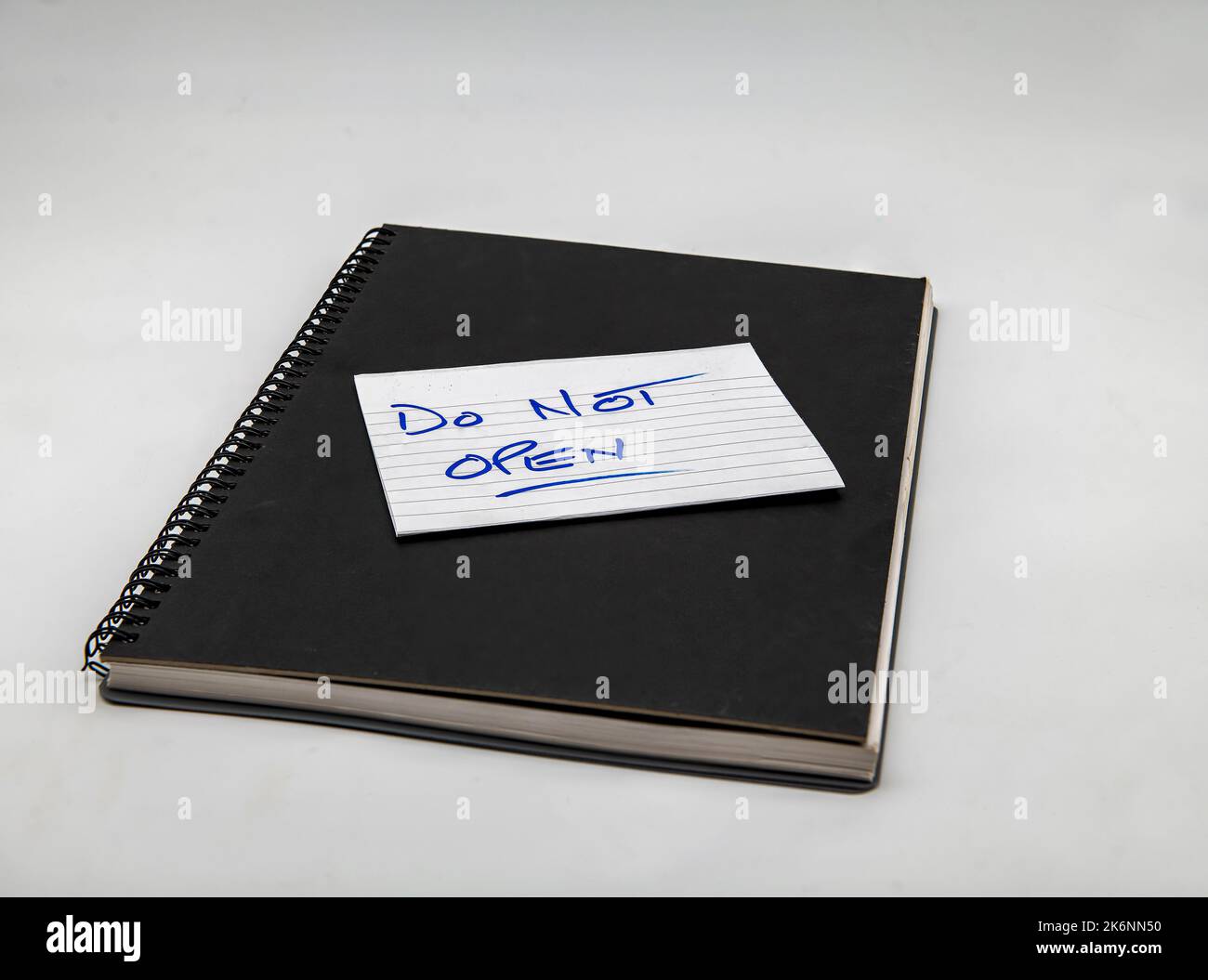 A black book with a note saying not to open isolated on a white ...
