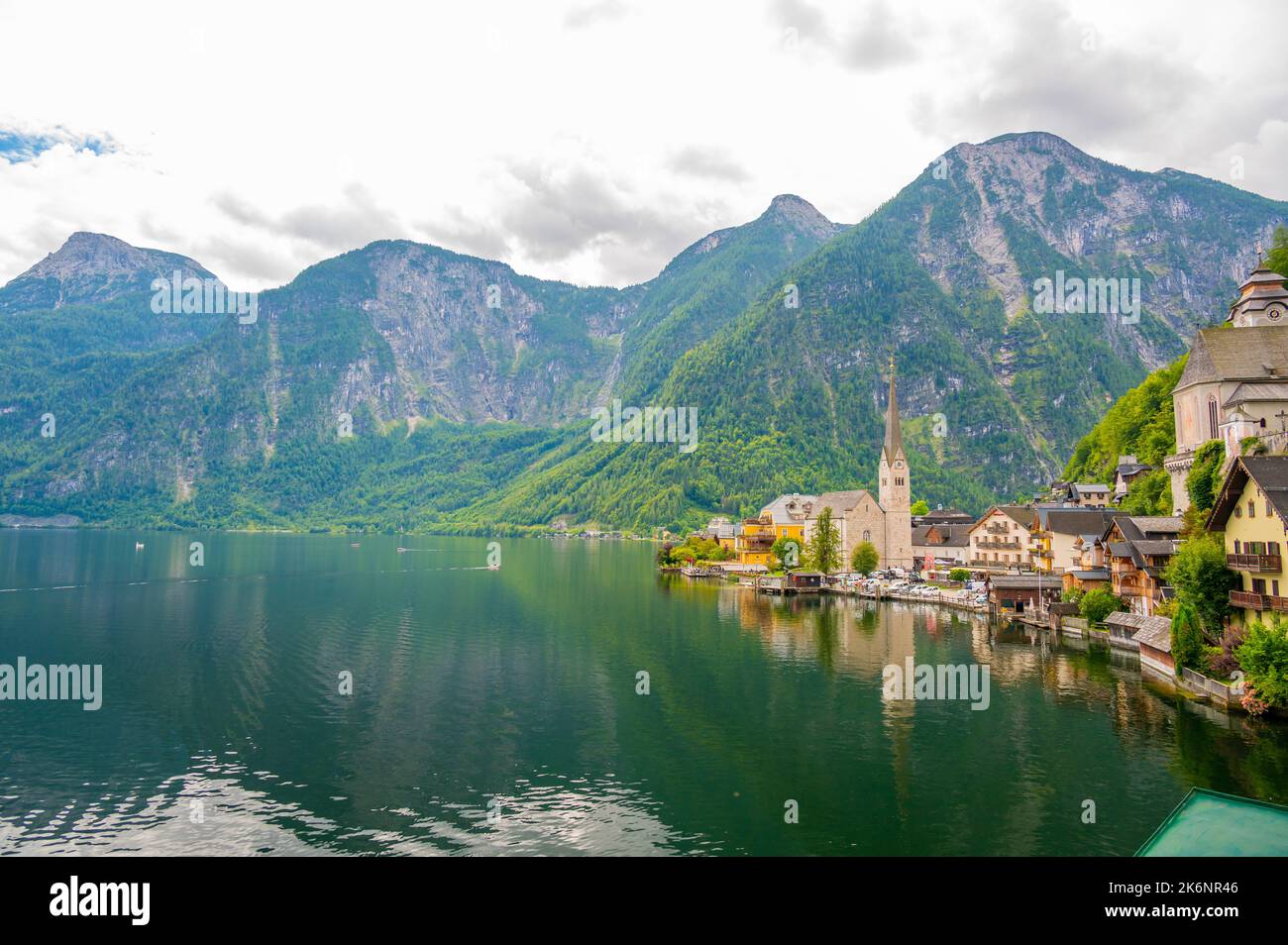 Famous view of Hallstatt city and church near the lake. Mountains in ...