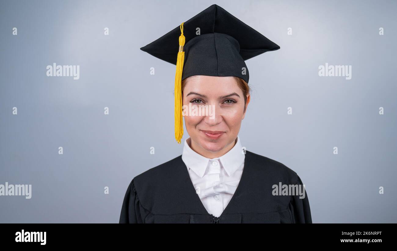 Smiling woman in graduation gown on white background Stock Photo - Alamy