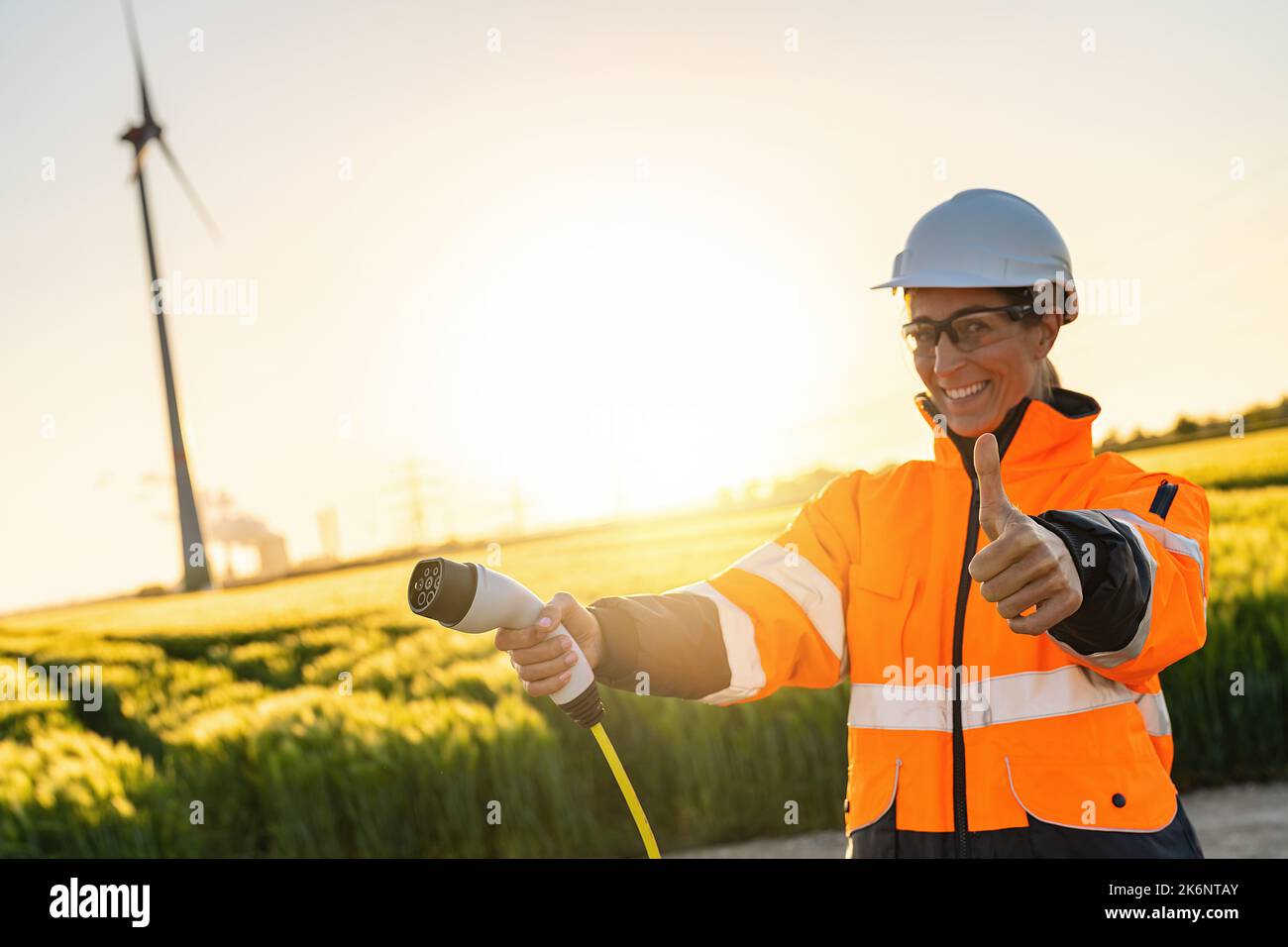 Female Work woman standing outside and holding power cable to charge a ...