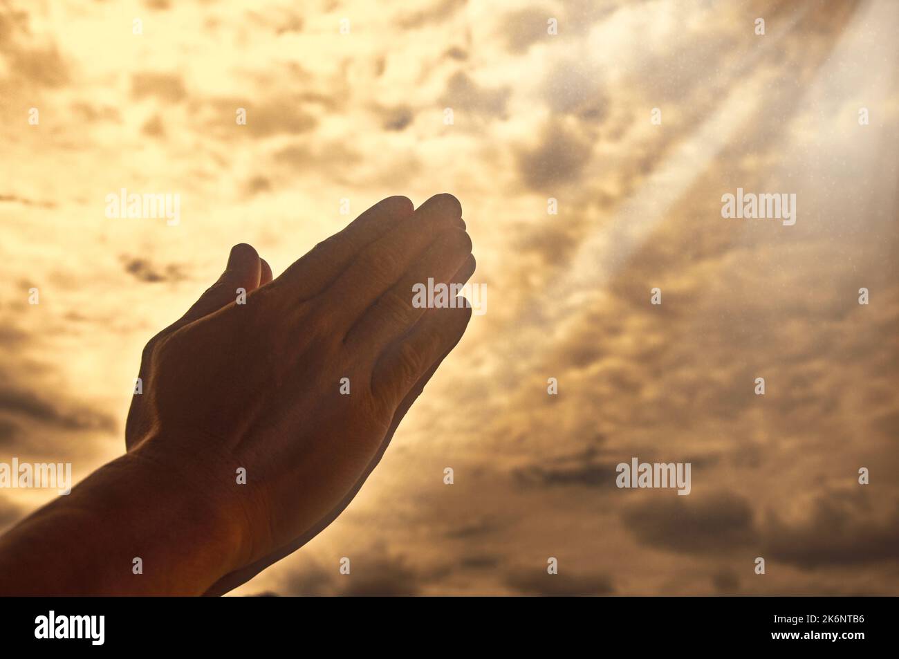 Hand praying with bright shining light on sky background. Religious and ...