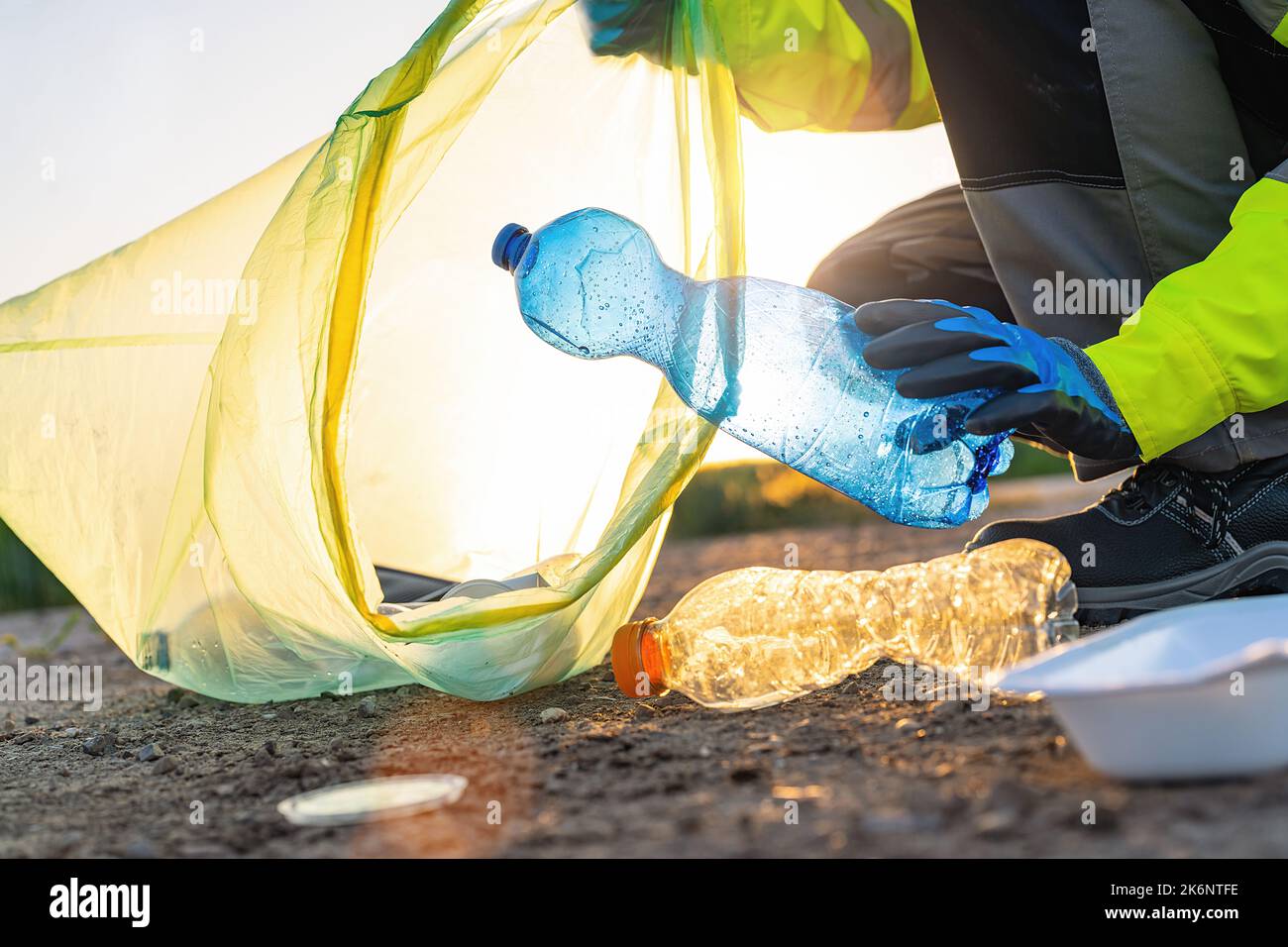 Man's hands pick up plastic bottles, put garbage in green garbage bag ...