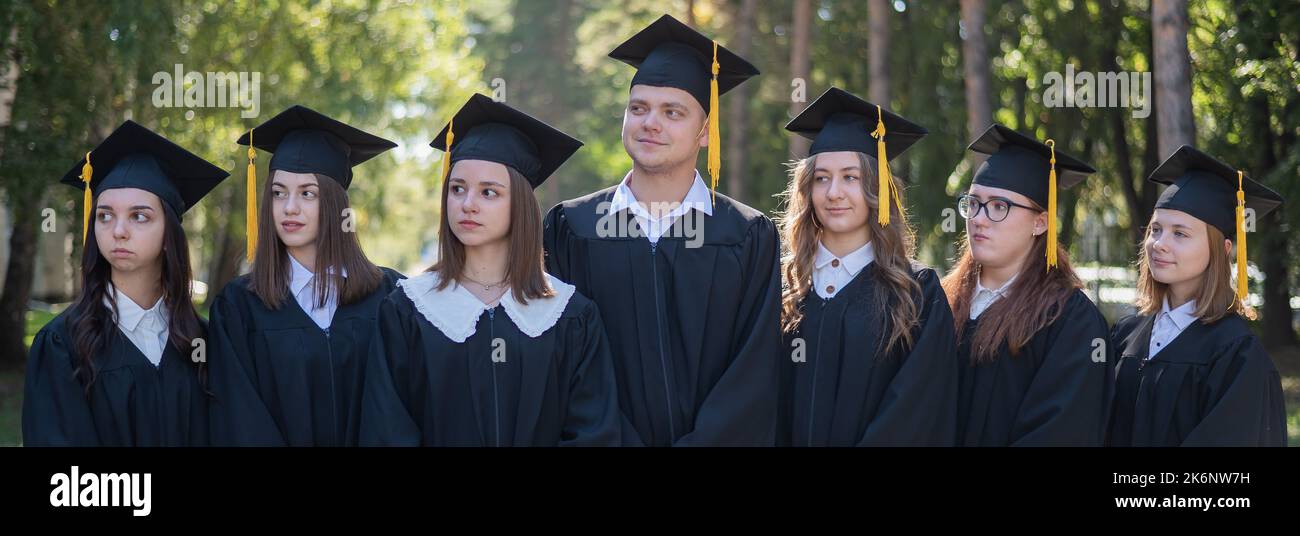 Seven graduates in robes stand in a row outdoors. Widescreen Stock ...