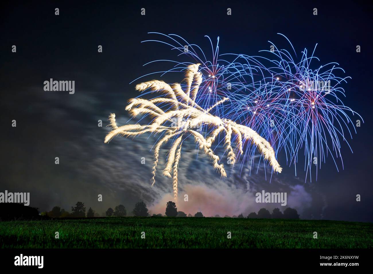 Fireworks with blue and yellow stars against dark night sky. Green ...