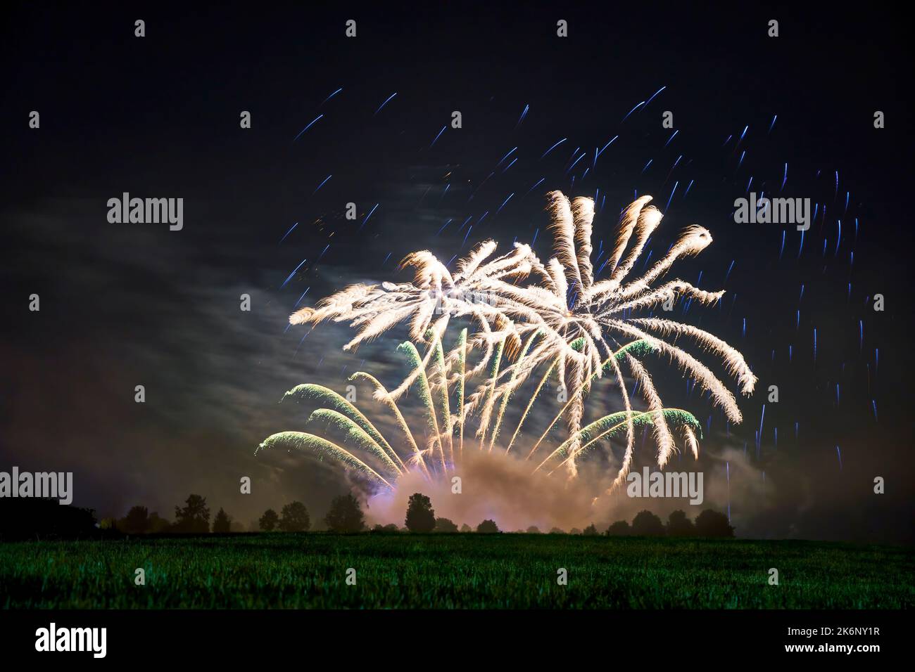 Fireworks with blue rain and yellow stars against dark night sky. Green ...
