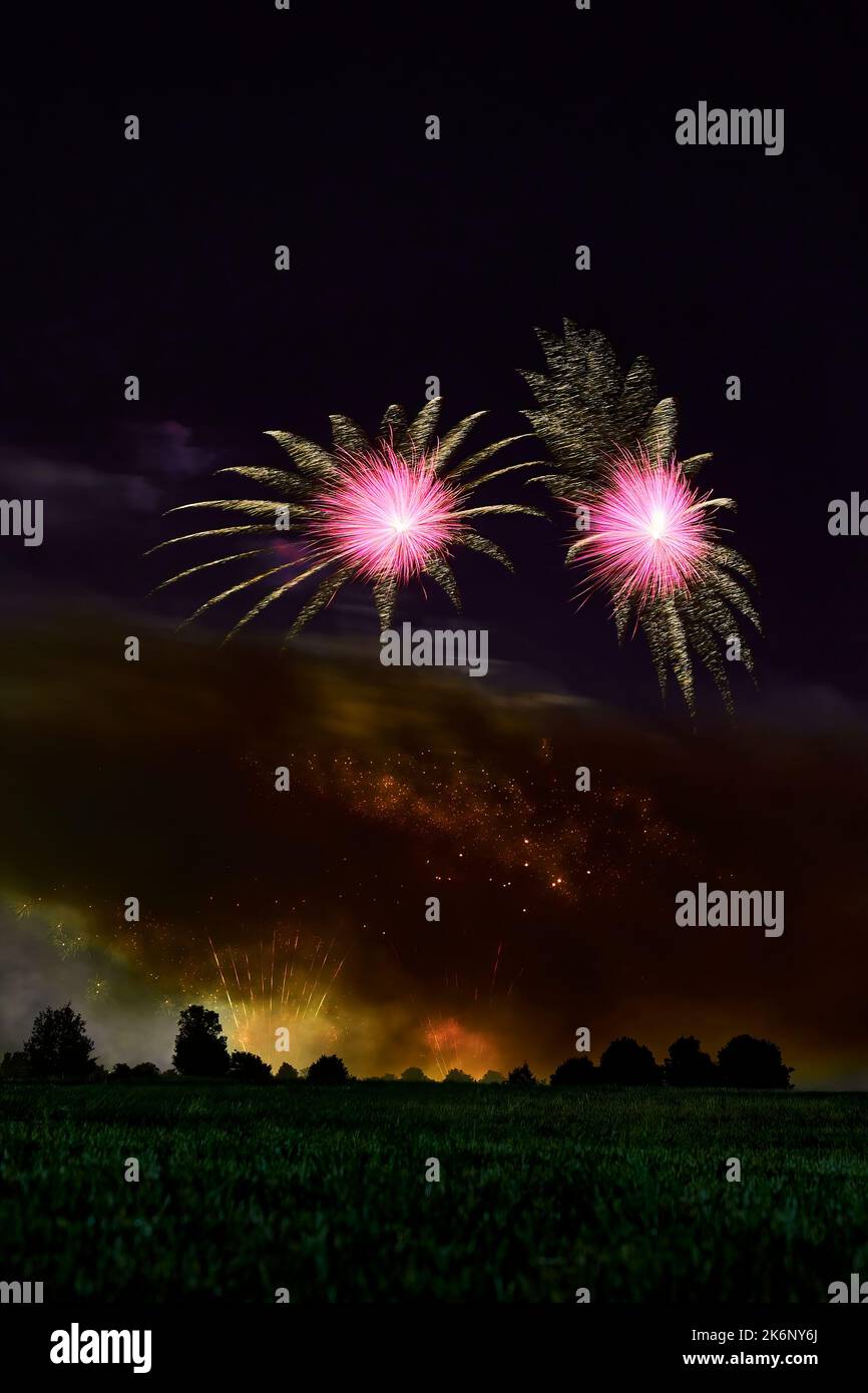 Fireworks with pink stars and yellow fountains against dark night sky ...