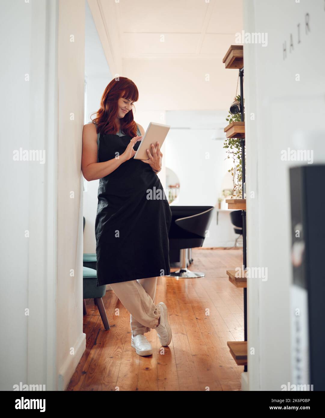 Technology, hairdresser and woman with tablet in hair salon on internet ...