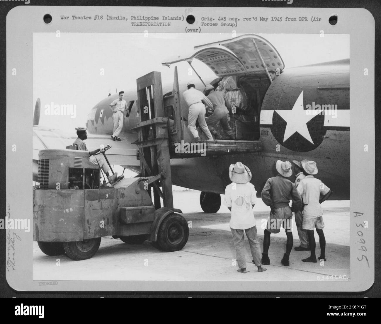 An Air Force engine is loaded aboard a Curtiss C-46 cargo plaen at an ...