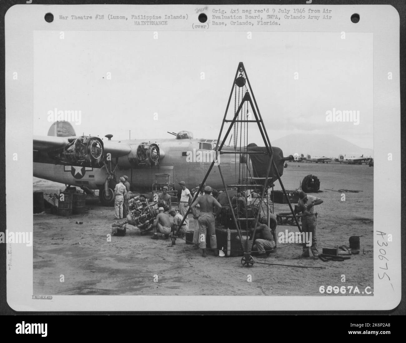 A ground crew changes two of the engines on a Consolidated B-24 ...