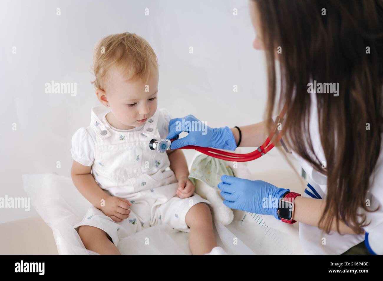 Female doctor checking child's lungs during medical checkup at the ...