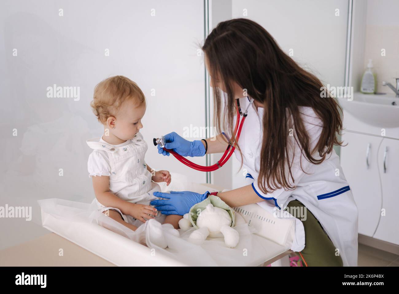 Female doctor checking child's lungs during medical checkup at the ...