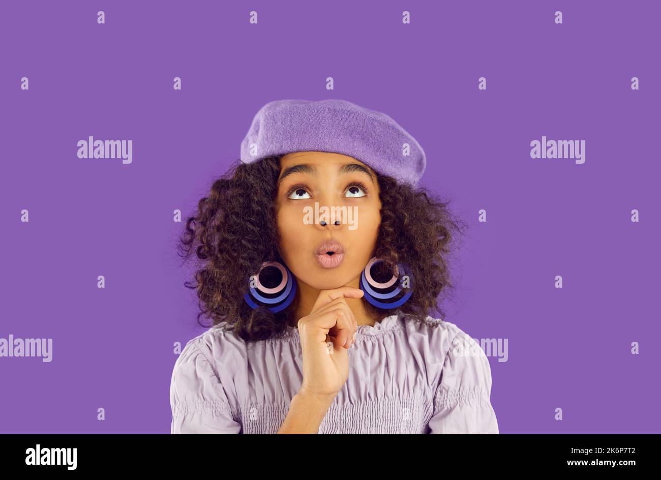 Young African American girl with delight and surprise looks up at copy ...