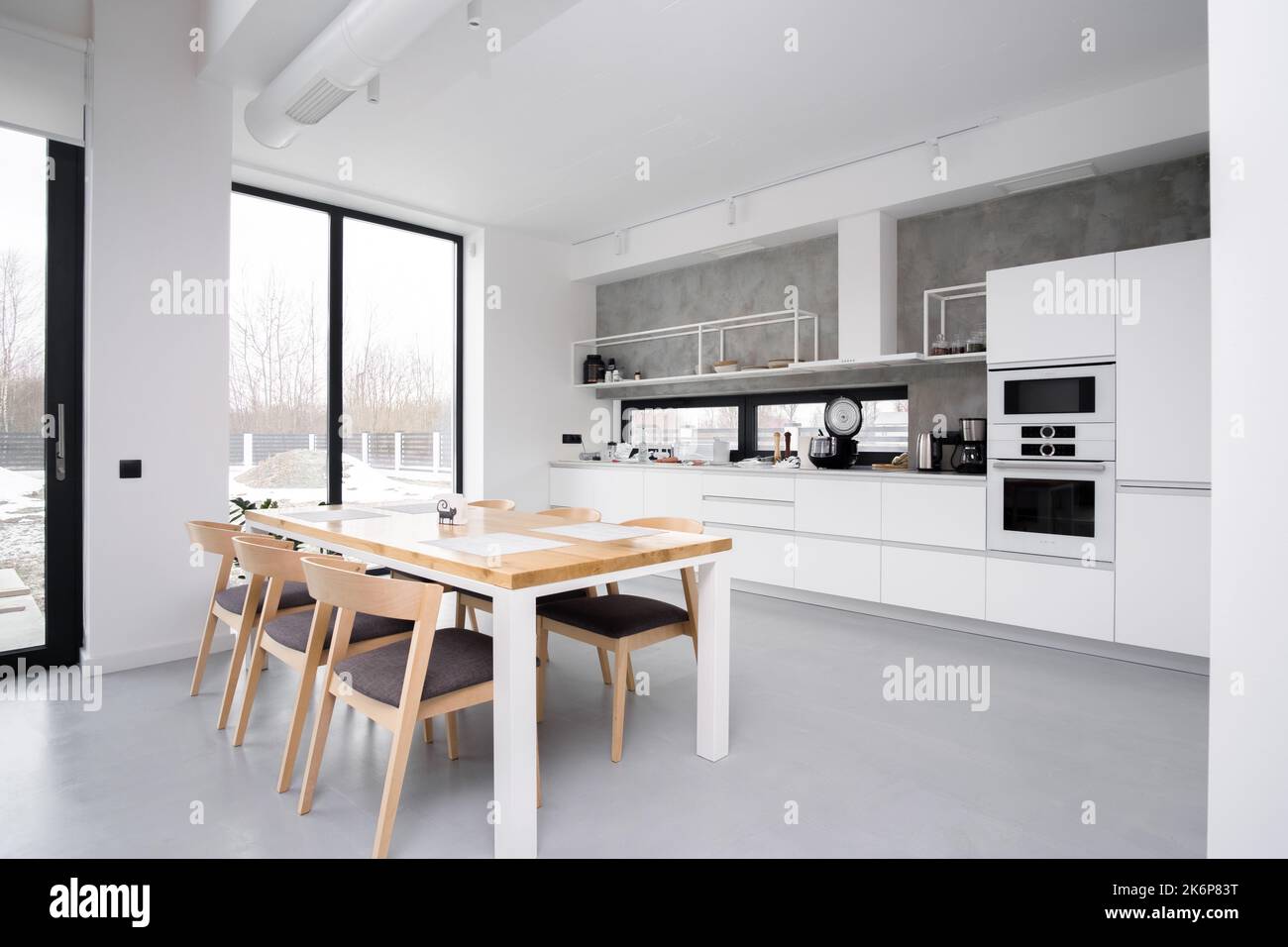 Elegant white kitchen interior with a large panoramic window without ...