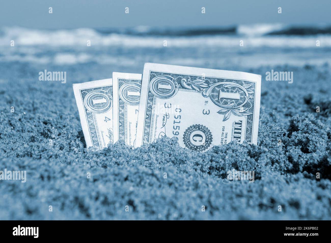 Paper bills one dollar buried in sand on beach backdrop of sea close-up ...