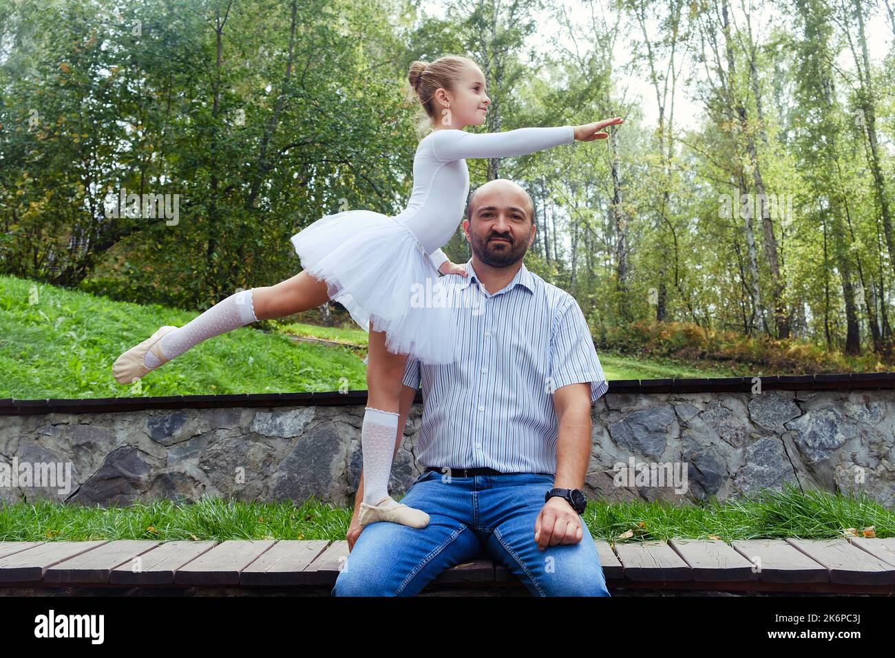 a little ballerina supported by her dad shows an element of ballet on a ...