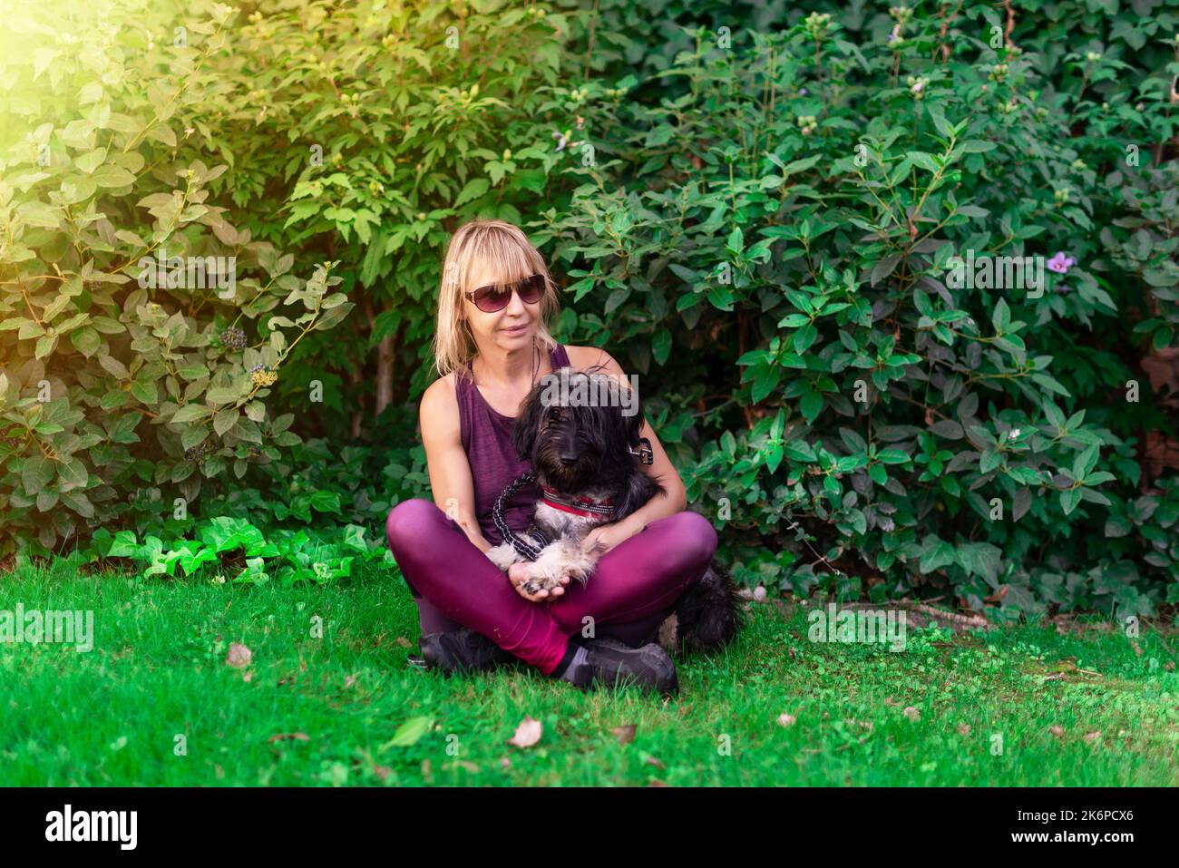 Blonde middle-aged woman with glasses sitting on the lawn with her ...