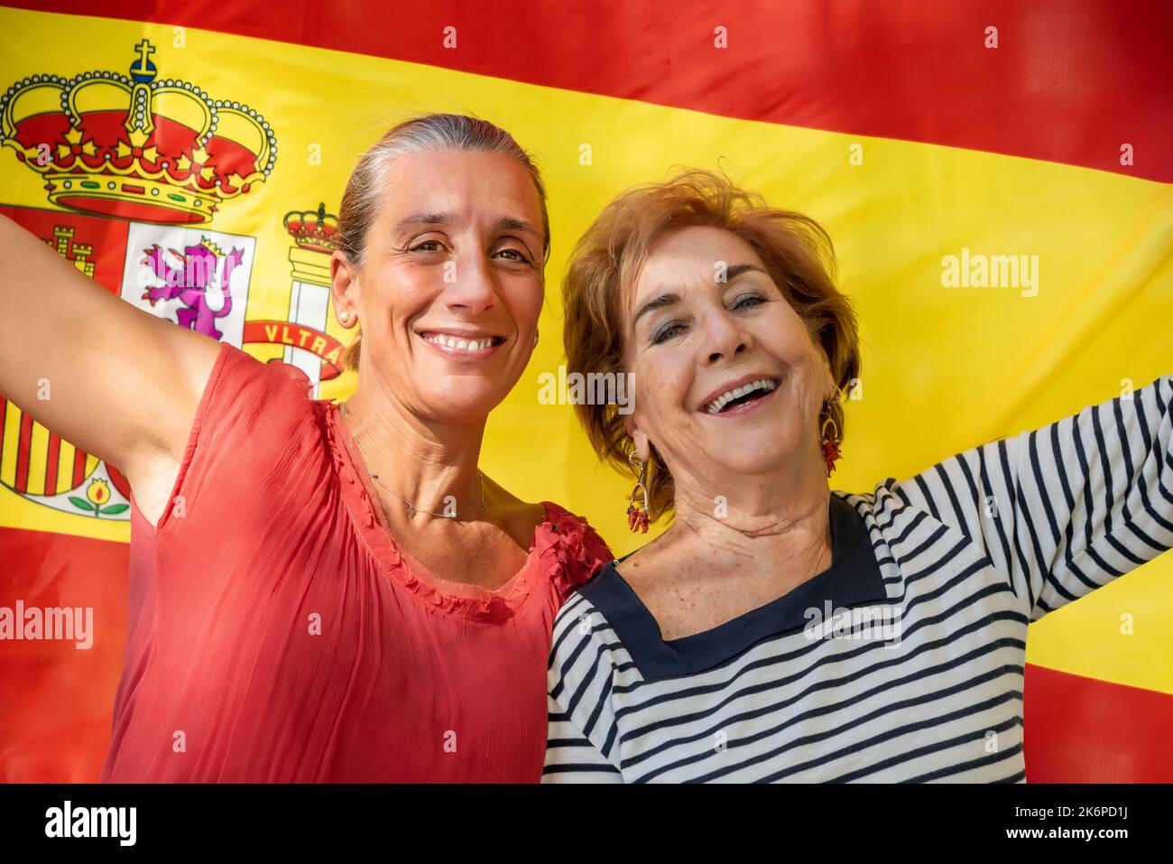 A middle-aged girl next to an older lady raising the red and yellow ...