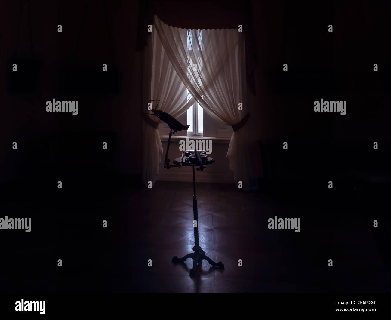 Old music room with a violin and music stand in the center, dark and ...