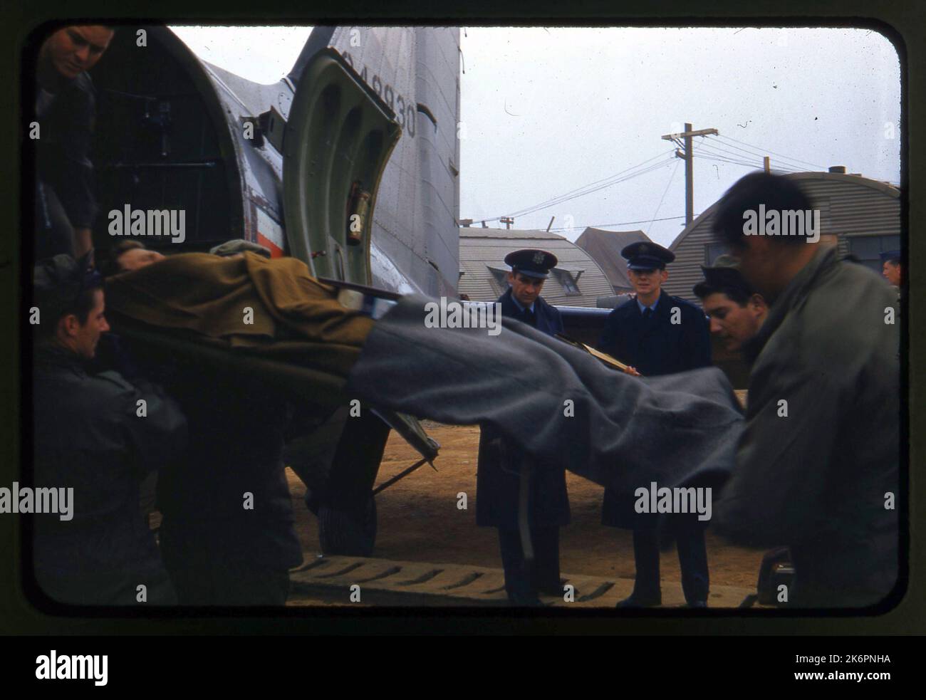 Four medics transport a wounded soldier on a stretcher onto a Douglas C ...