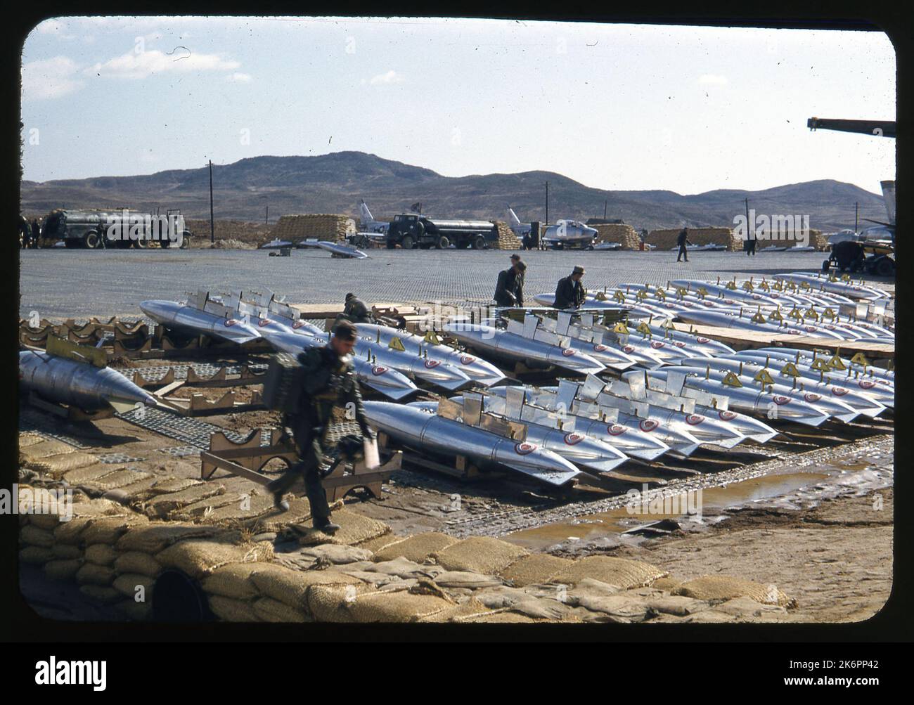 An airfield somewhere in Korea, with rows of external fuel tanks. A ...