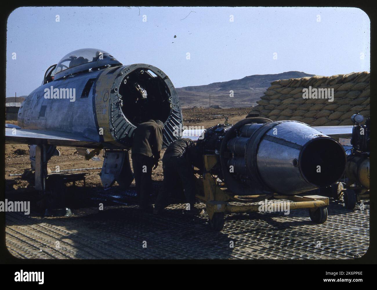 Two technicians bend over to examine some part of the engine of a North ...
