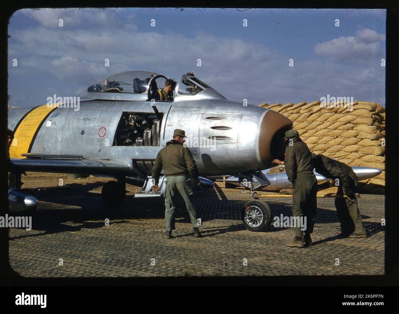 Right side view of a North American F-86 Sabre. Three technicians stand ...
