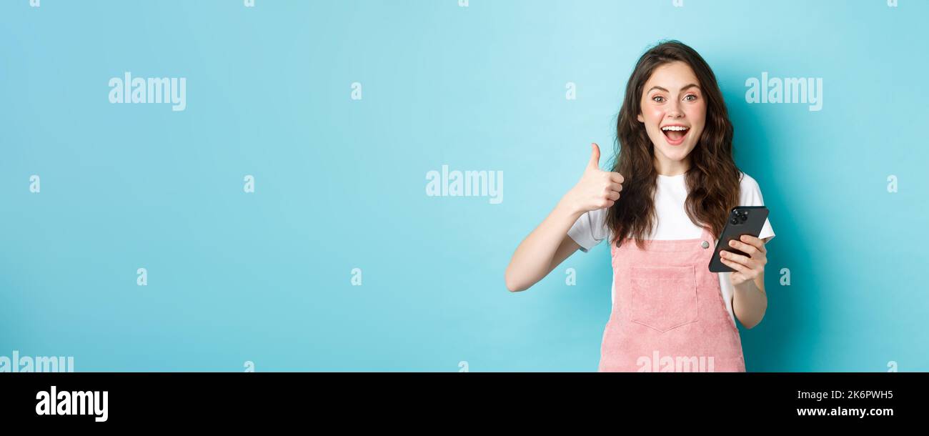 Portrait of excited cute girl say yes, smiling and nod in approval ...