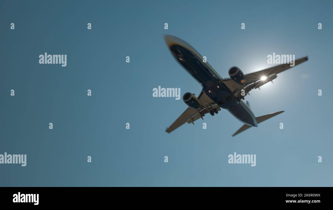 Airplane flying in a blue sky Stock Photo - Alamy