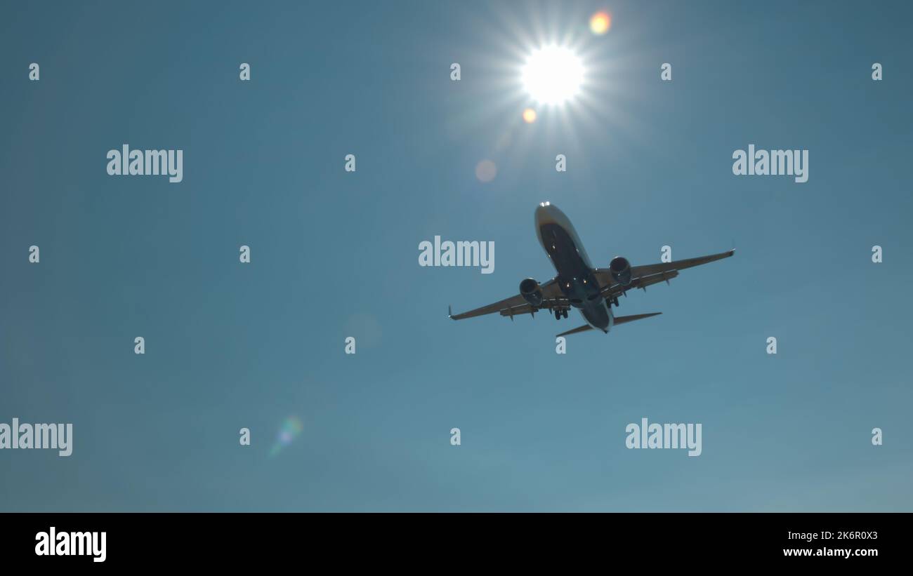 Airplane flying in a blue sky Stock Photo - Alamy