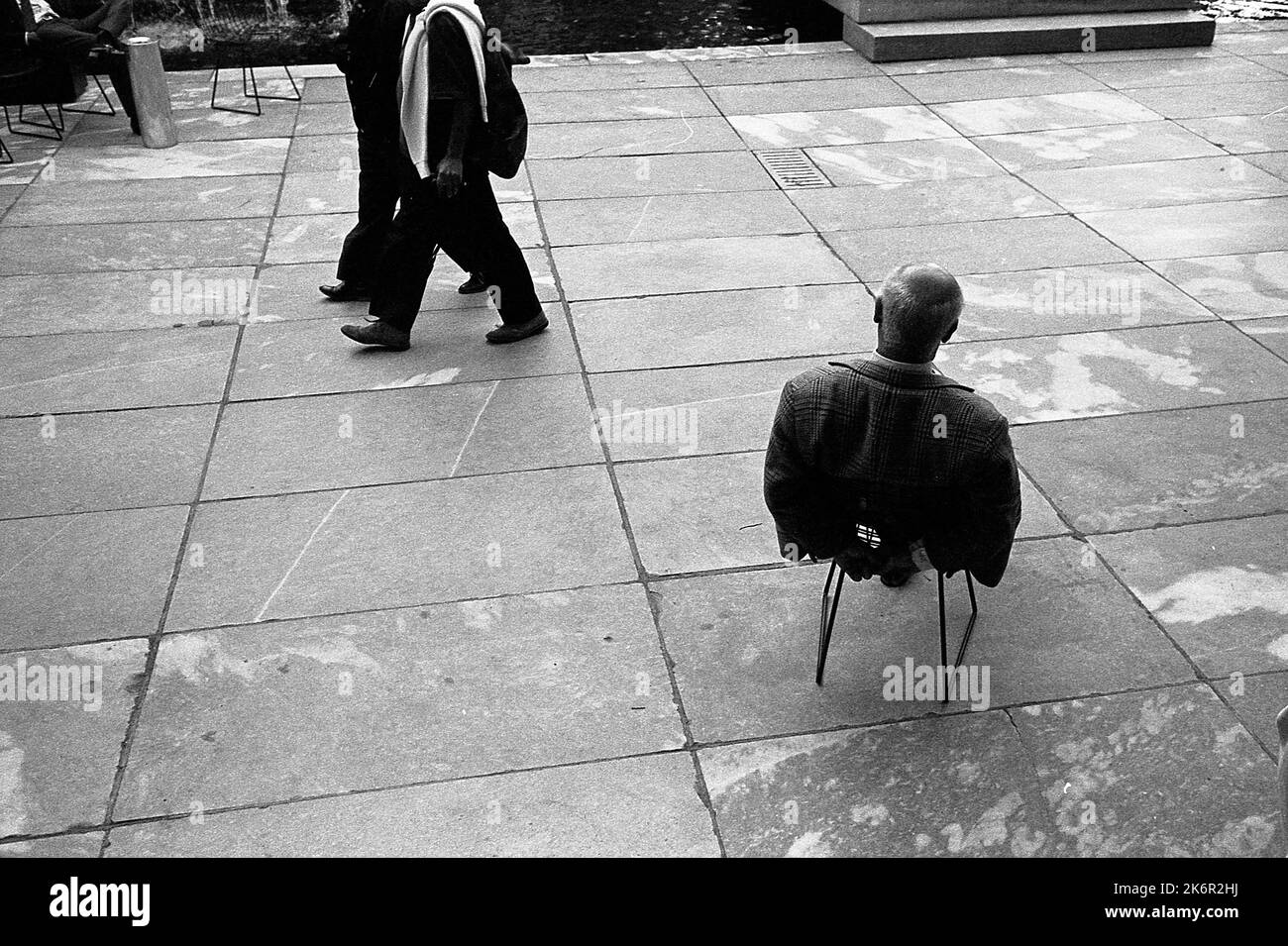 Street scene with a walking passerby couple and a sitting man which ...