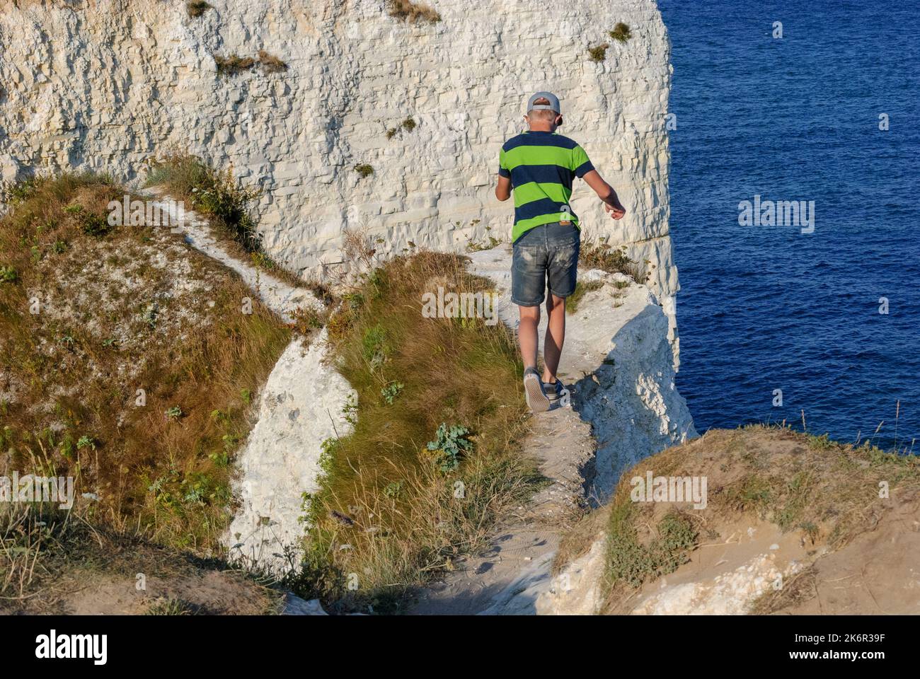 Youths walking on dangerous narrow clifftop footpath, Old Harry Rocks ...