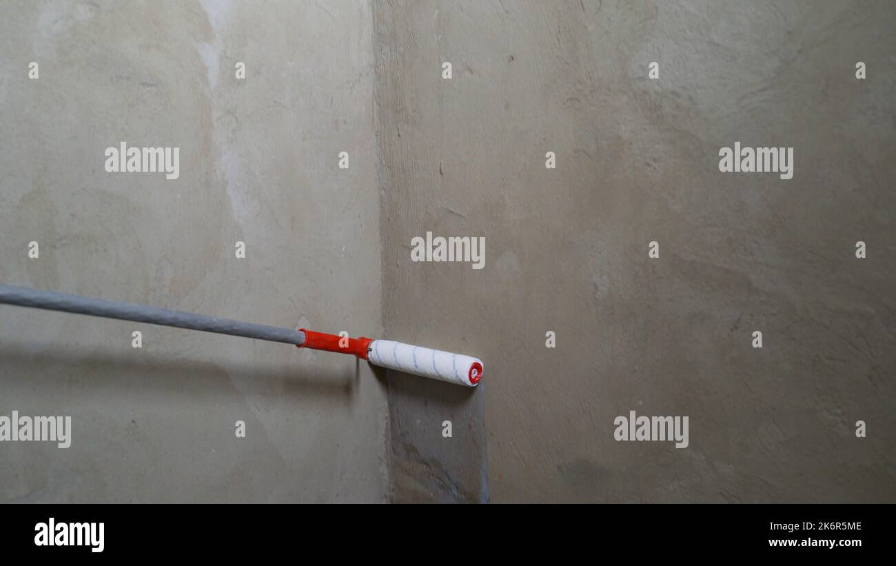 The process of applying a primer to a concrete wall using a roller. The ...