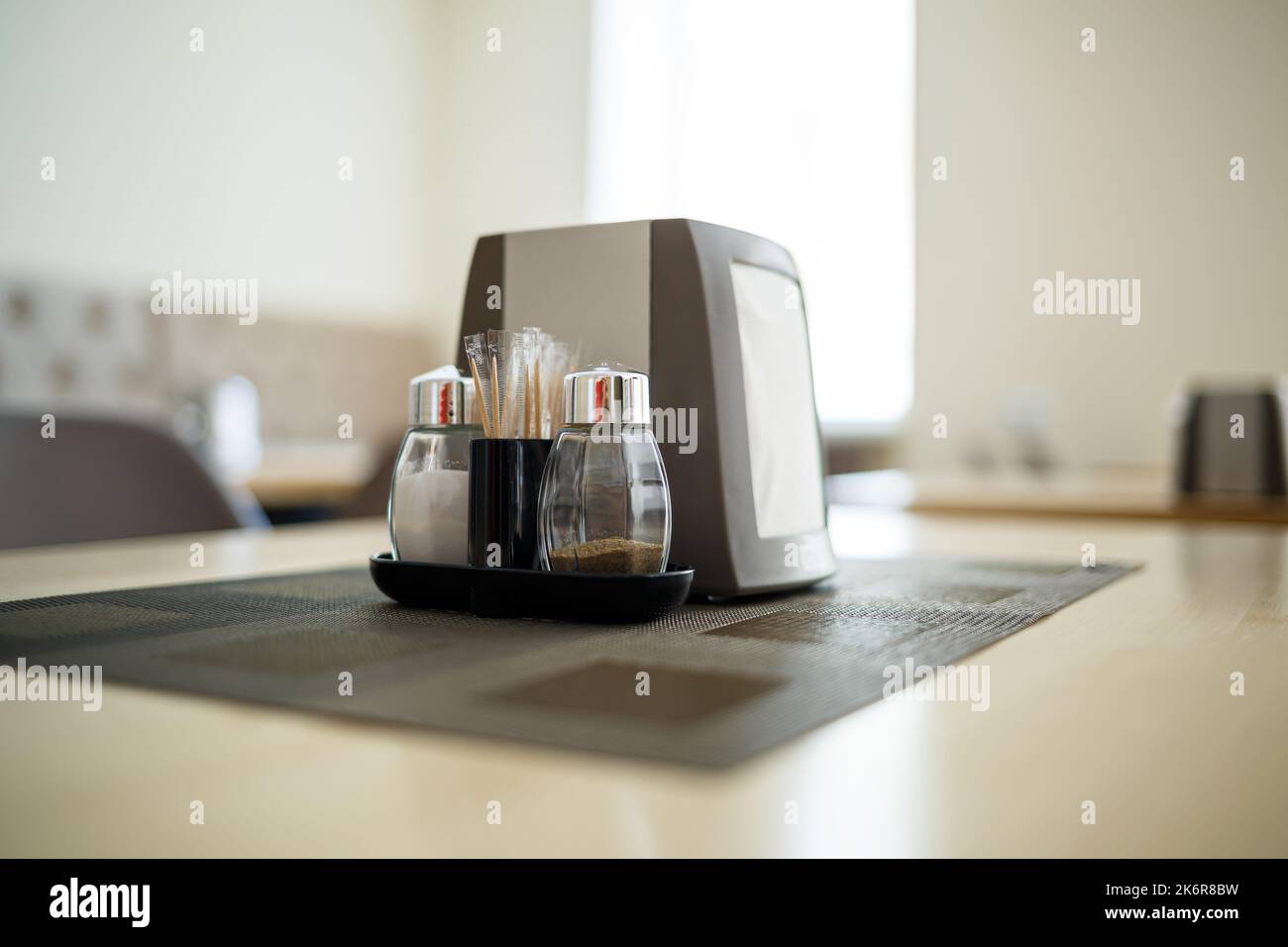 Wooden table with serving, salt and pepper, napkin holder, cup of black ...